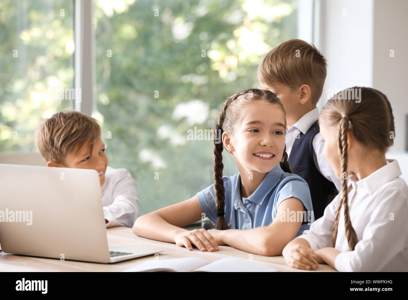Cute little pupils with laptop in classroom Stock Photo - Alamy