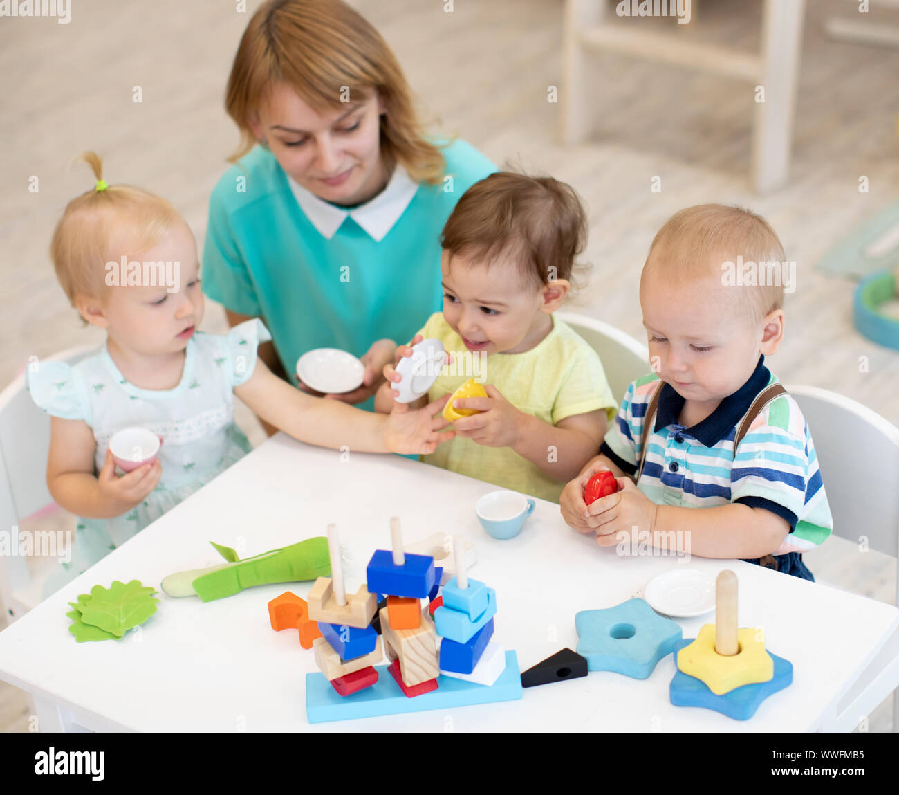 Nursery school children and teacher playing with toys Stock Photo - Alamy