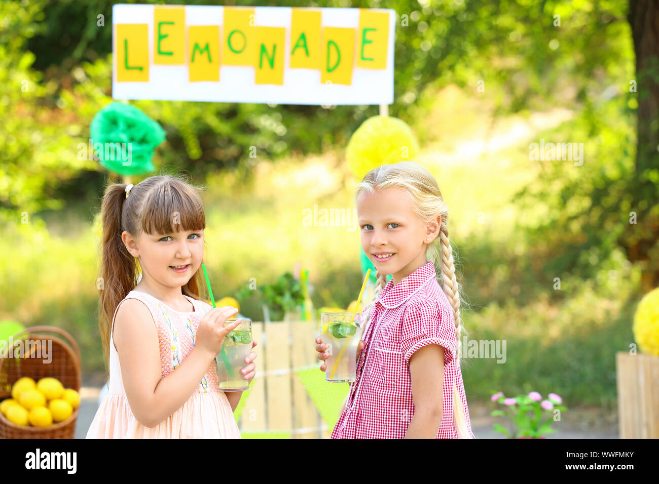 Cute little girls drinking lemonade in park Stock Photo - Alamy