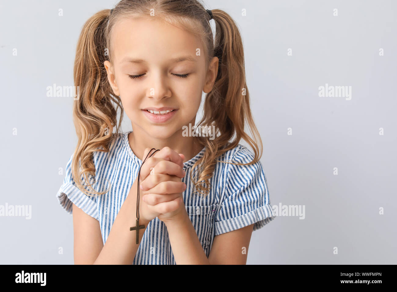 Praying little girl on light background Stock Photo - Alamy