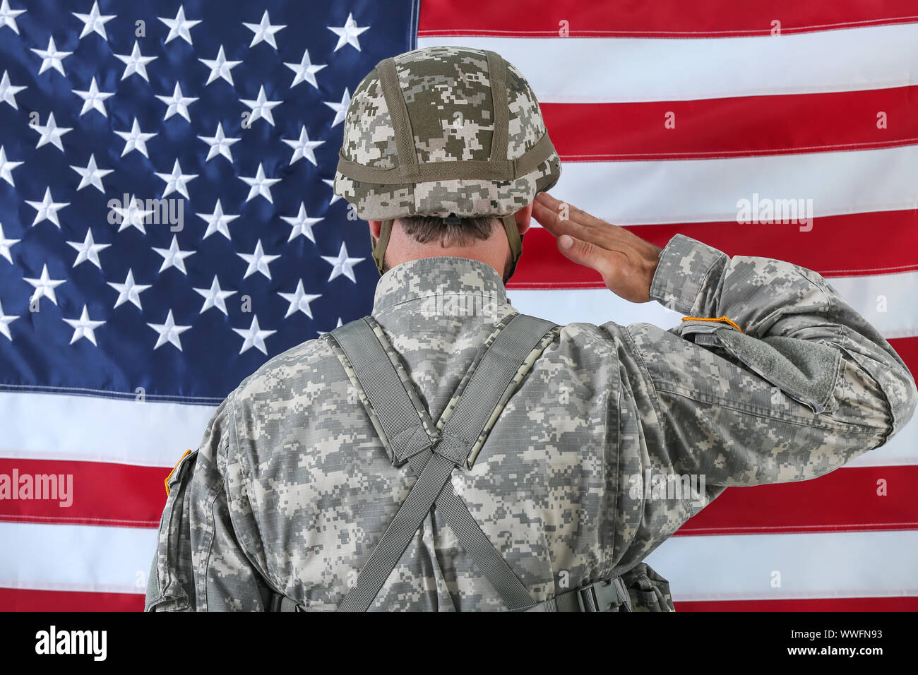 Saluting soldier with national flag of USA on background, back view ...