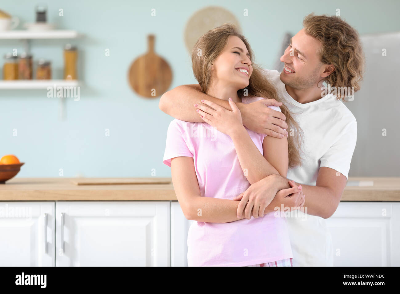 Happy young couple hugging in kitchen Stock Photo - Alamy