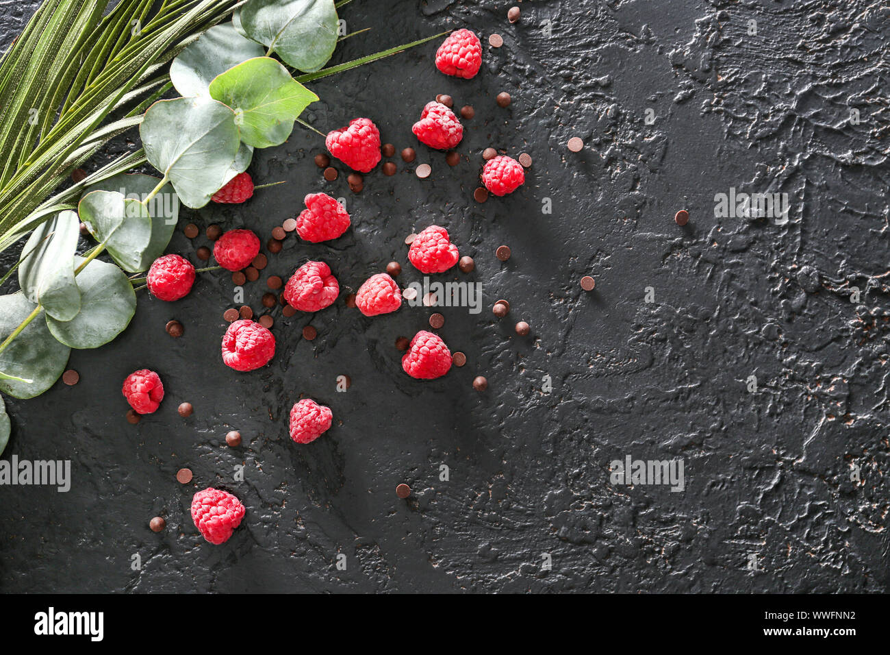 Fresh raspberries with tropical leaves on dark background Stock Photo ...