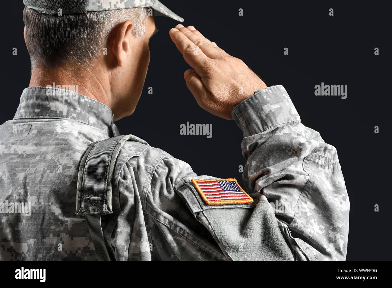 Saluting male soldier on dark background Stock Photo - Alamy