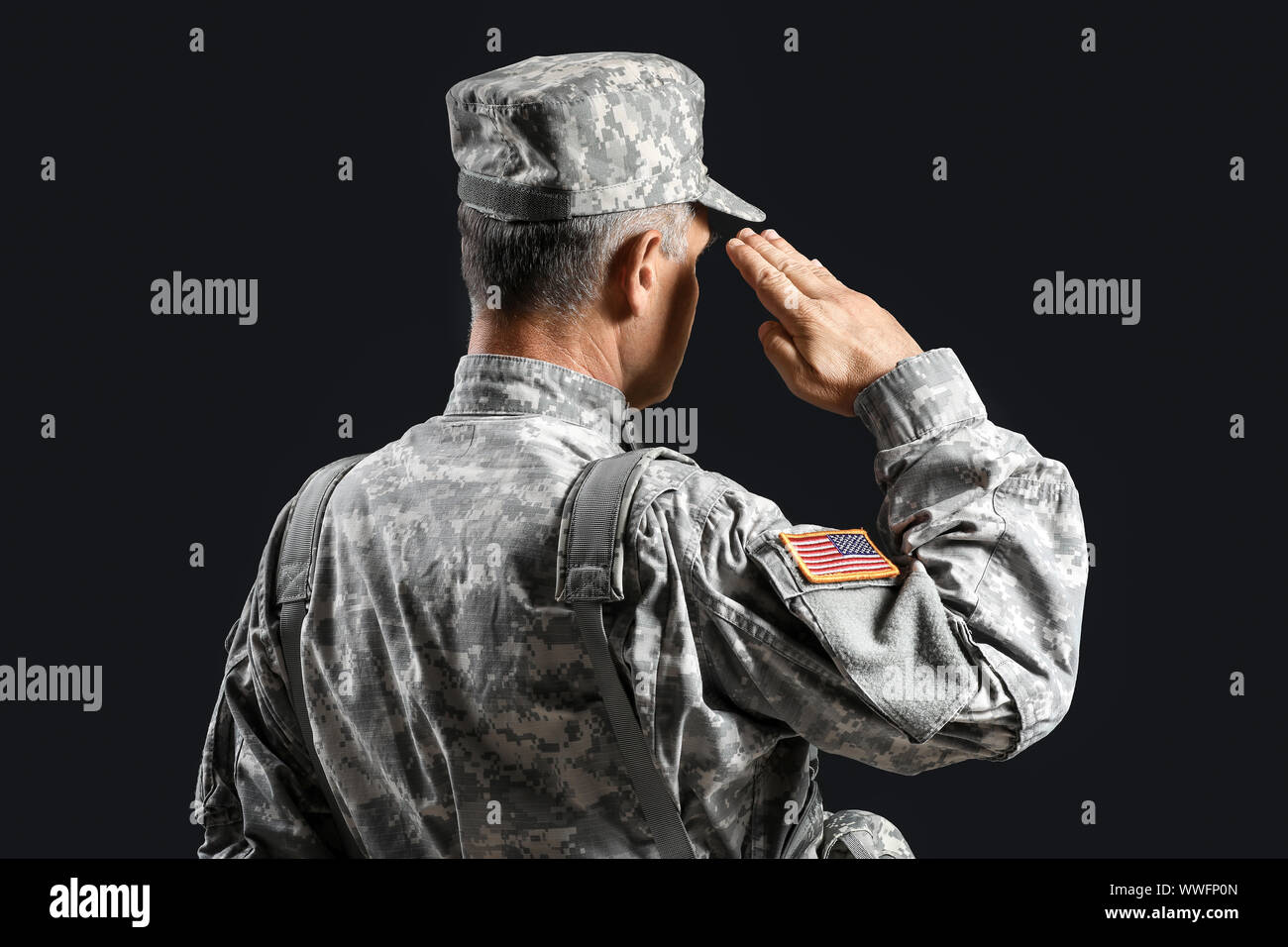Saluting male soldier on dark background Stock Photo - Alamy