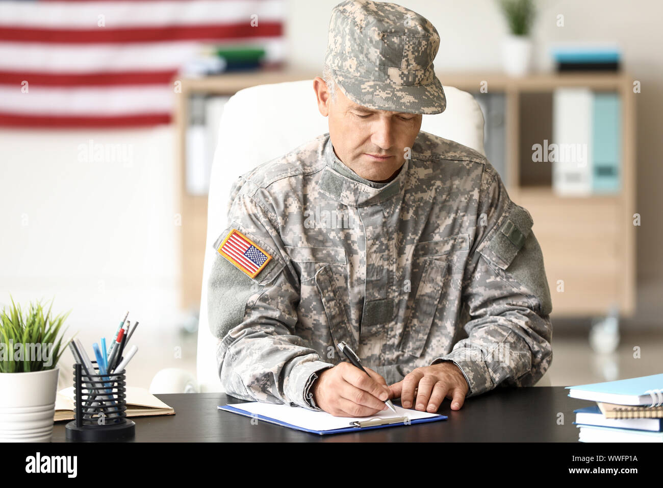 Mature male soldier writing report in headquarters building Stock Photo ...