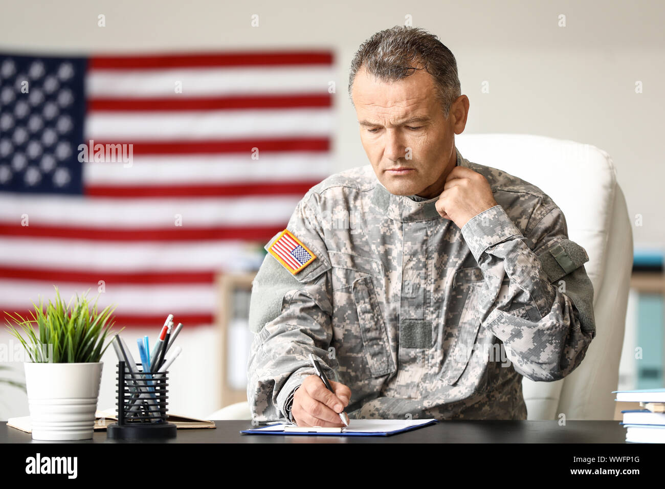 Mature male soldier writing report in headquarters building Stock Photo ...
