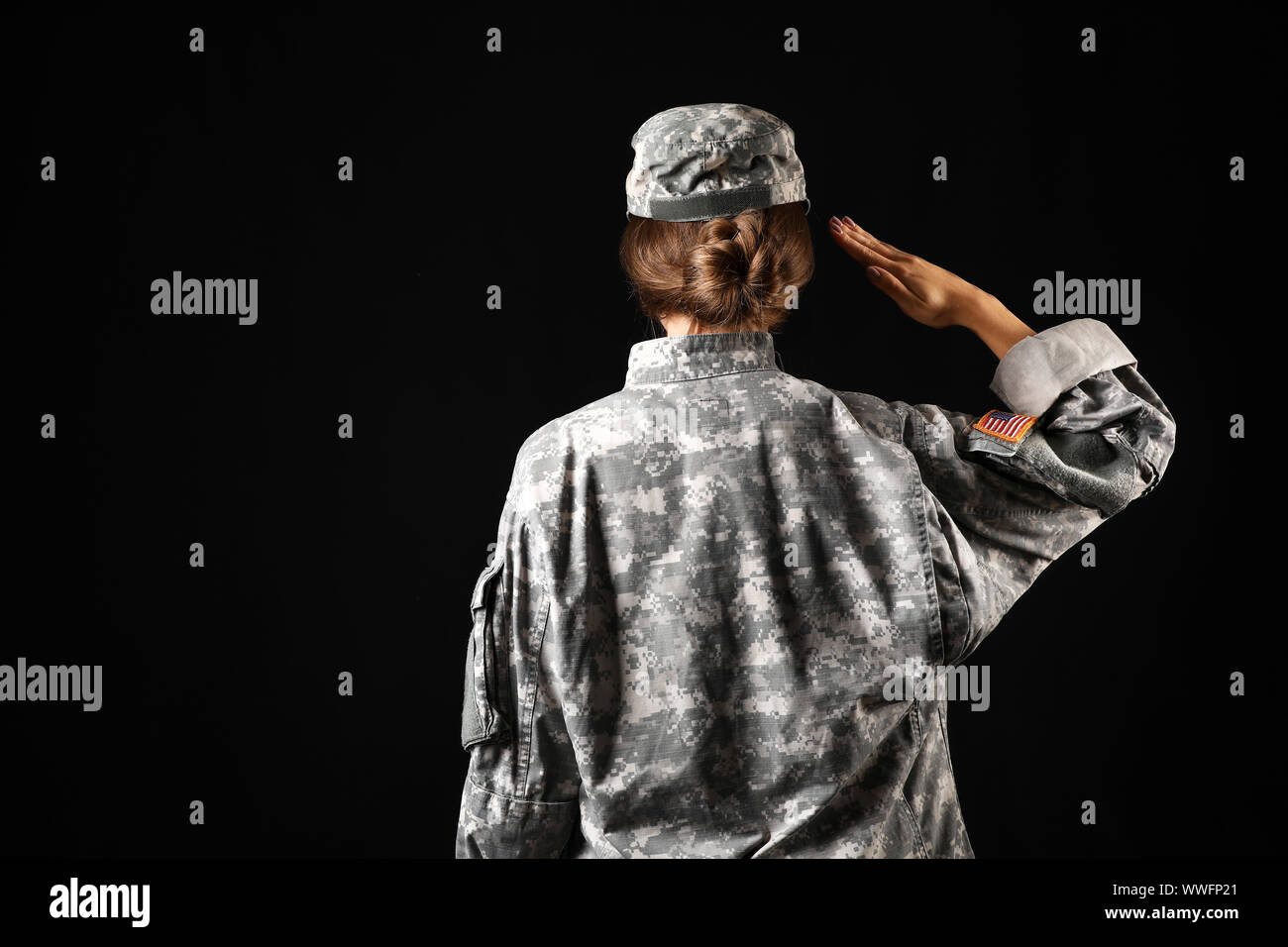 Saluting female soldier on dark background, back view Stock Photo - Alamy
