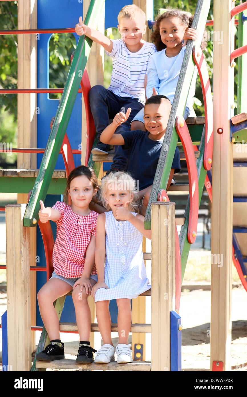 Cute little children showing thumb-up gesture on playground outdoors ...