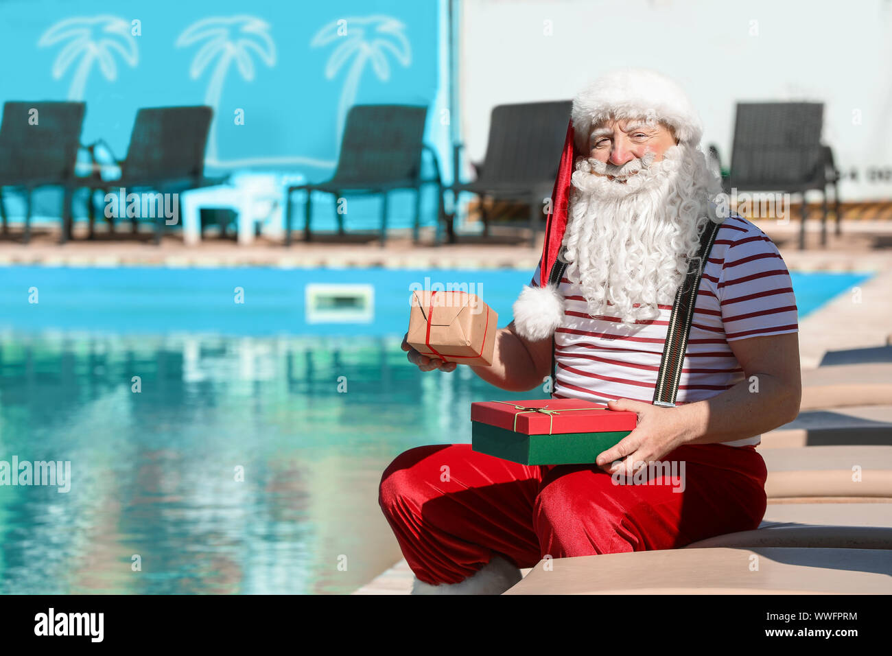 Santa Claus with gifts sitting on the edge of swimming pool Stock Photo ...