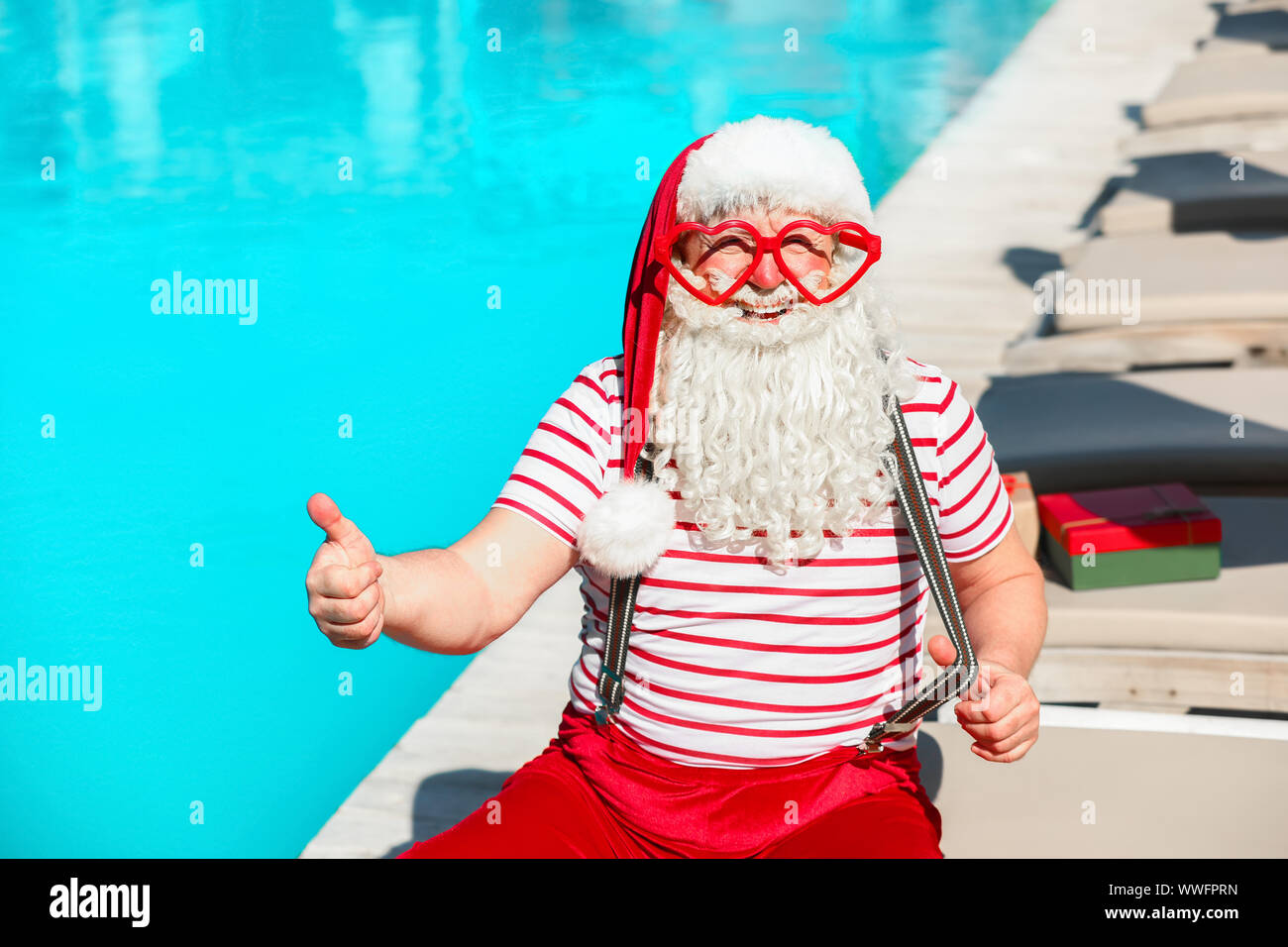 Santa Claus showing thumb-up near swimming pool at resort Stock Photo ...