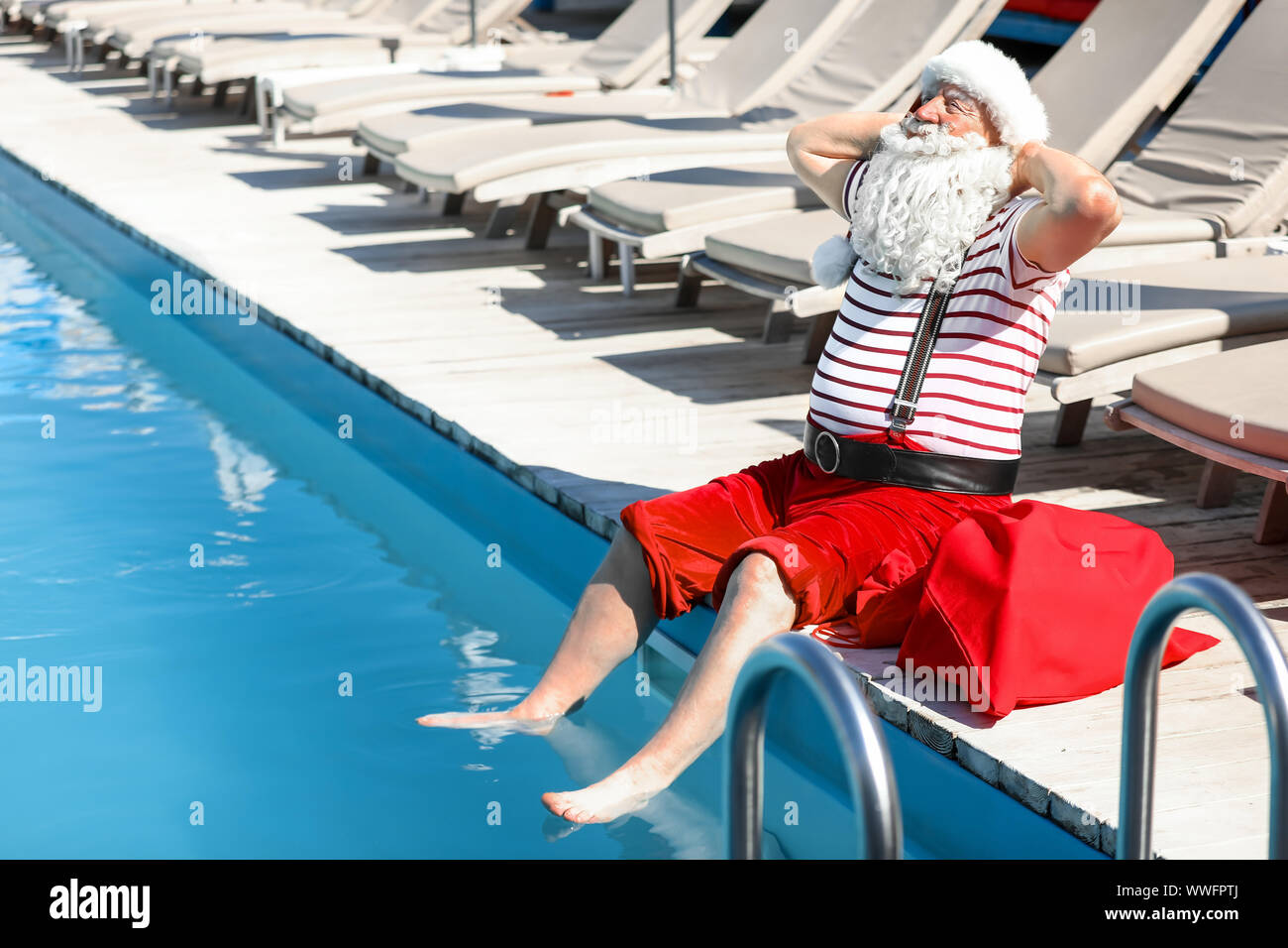 Santa Claus sitting on the edge of swimming pool at resort Stock Photo ...