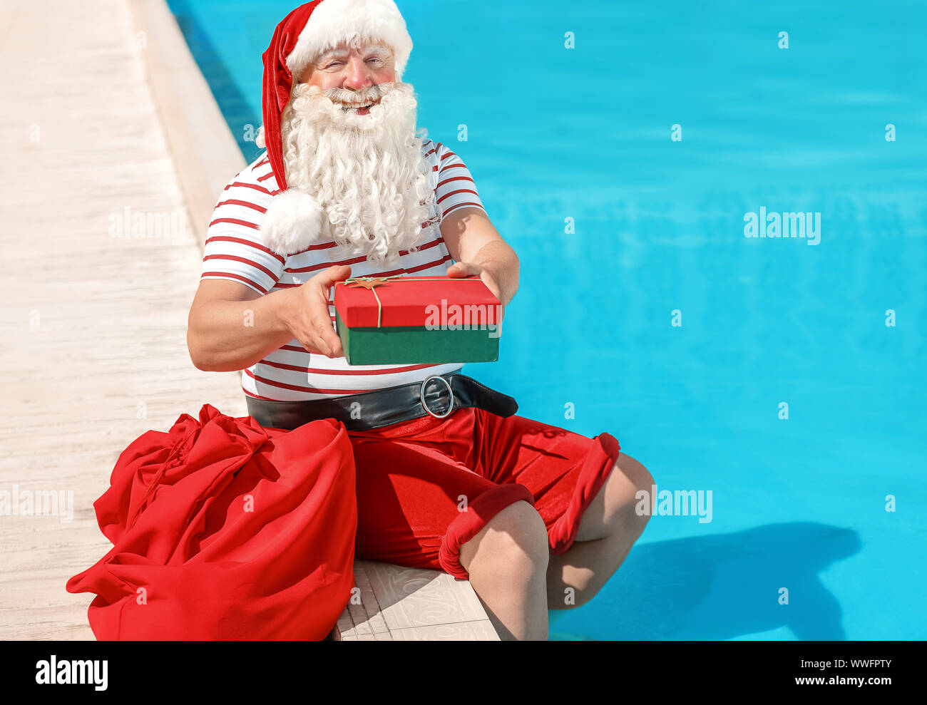Santa Claus with gift near swimming pool at resort Stock Photo - Alamy
