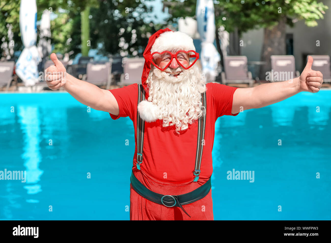 Santa Claus showing thumb-up near swimming pool at resort Stock Photo ...