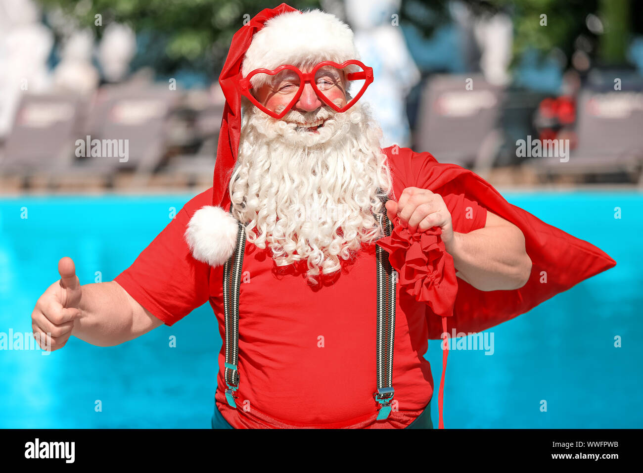 Santa Claus showing thumb-up near swimming pool at resort Stock Photo ...