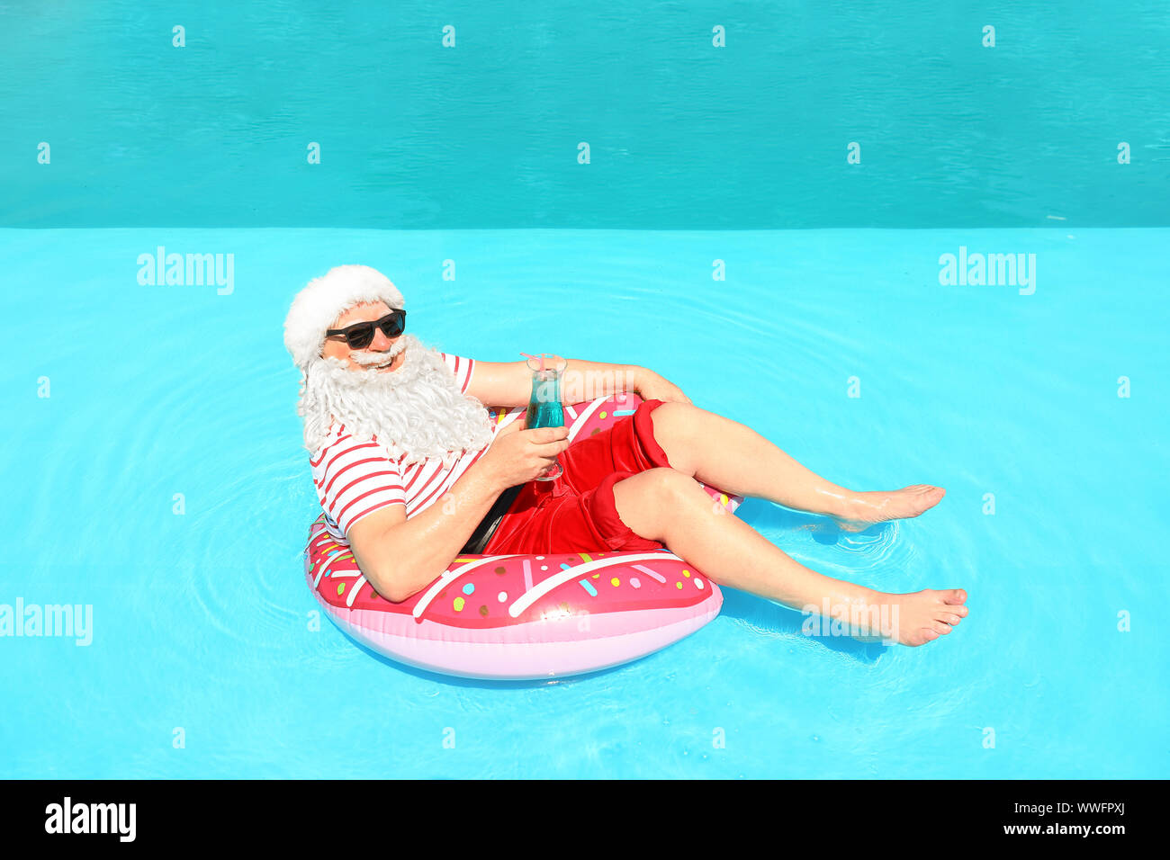 Santa Claus relaxing on inflatable ring in swimming pool Stock Photo ...