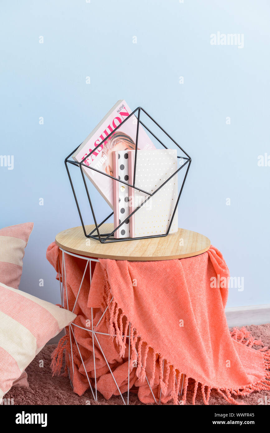 Stylish holder with books and magazine on table in room Stock Photo - Alamy