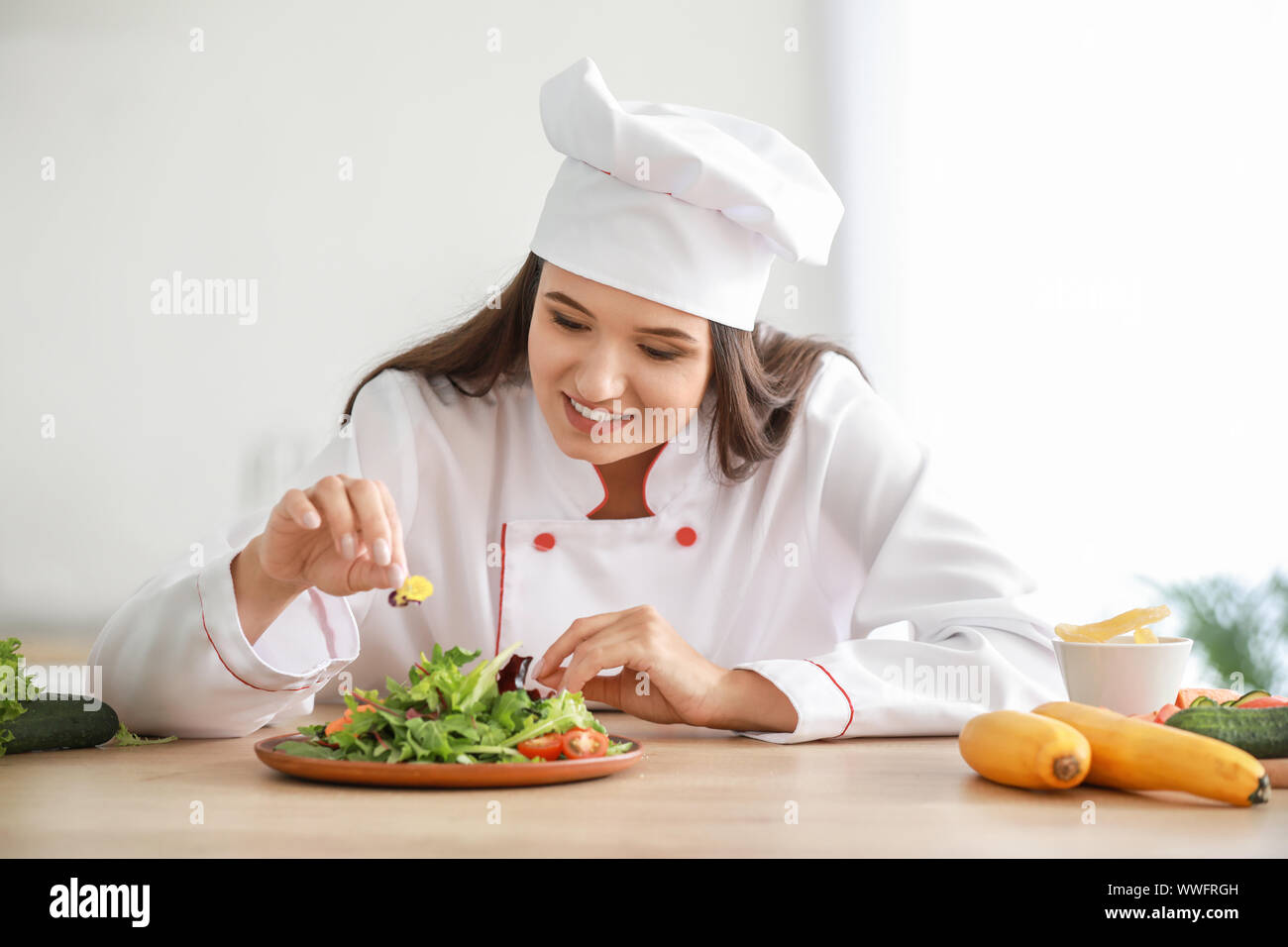 Beautiful female chef with salad in kitchen Stock Photo - Alamy