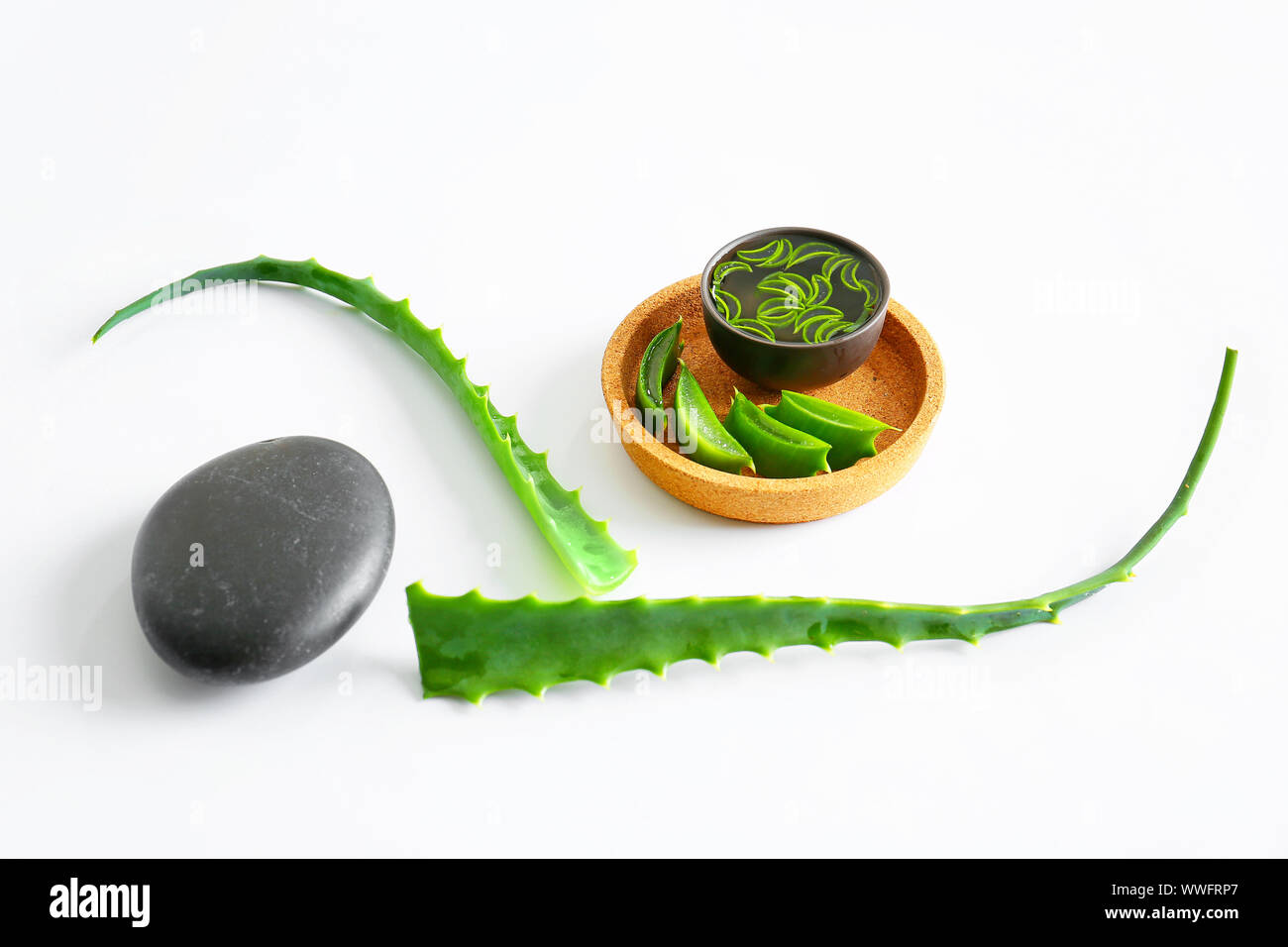 Fresh aloe vera leaves with juice and spa stone on white background ...