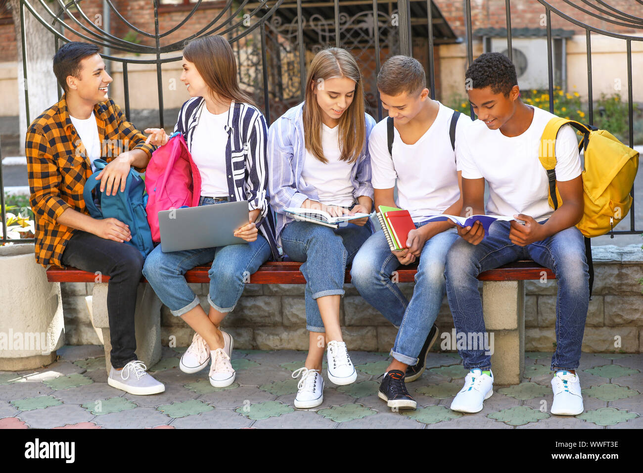Young students sitting on bench outdoors Stock Photo - Alamy