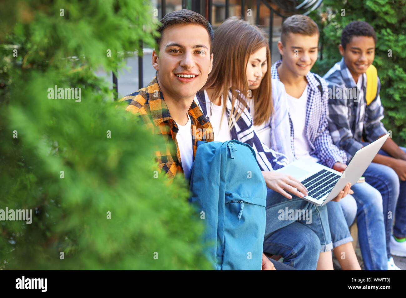 Young students sitting on bench outdoors Stock Photo - Alamy