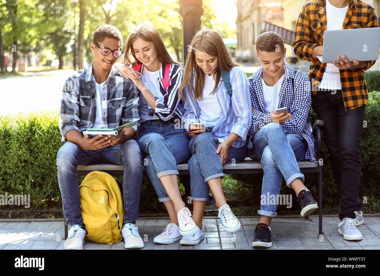 Young students sitting on bench outdoors Stock Photo - Alamy