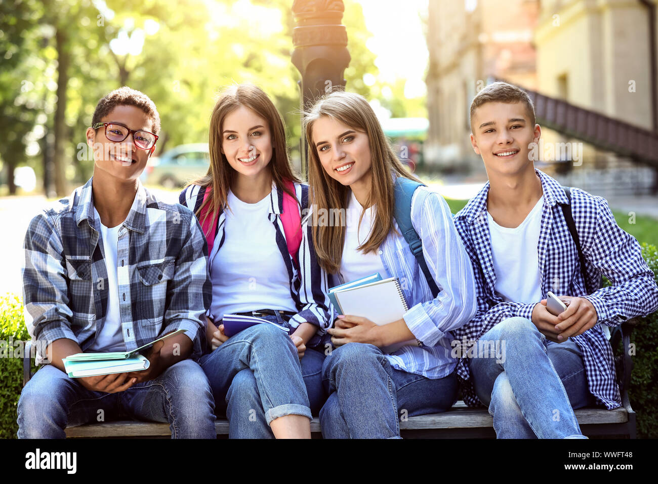 Young students sitting on bench outdoors Stock Photo - Alamy