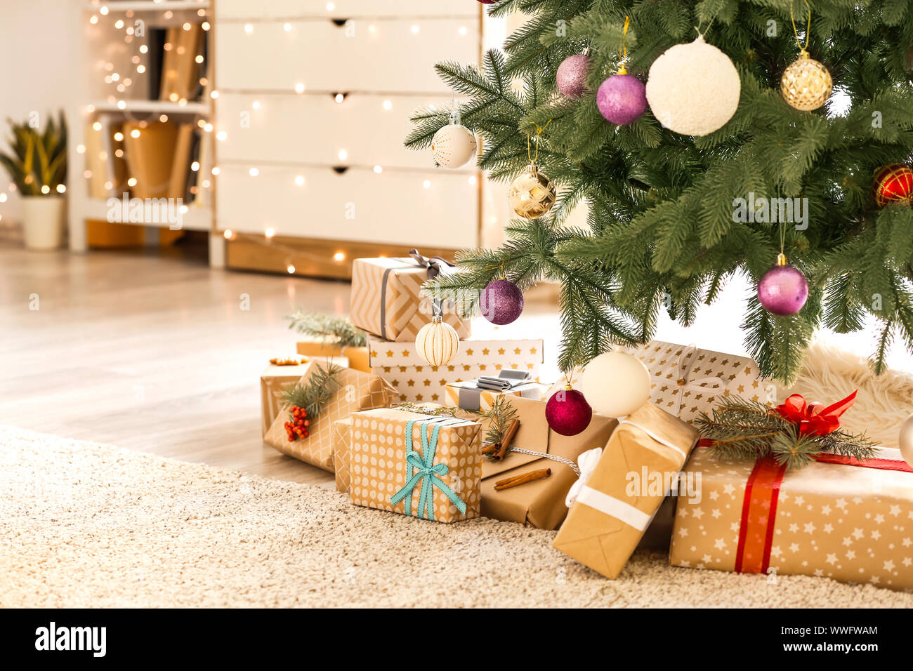 Beautiful gift boxes under fir tree in room Stock Photo - Alamy