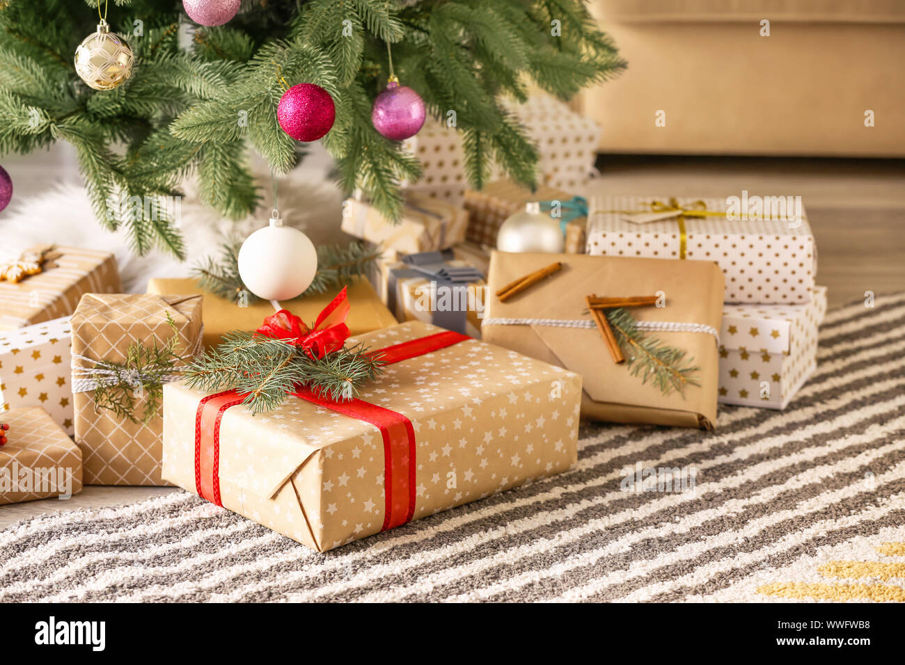 Beautiful gift boxes under fir tree in room Stock Photo - Alamy