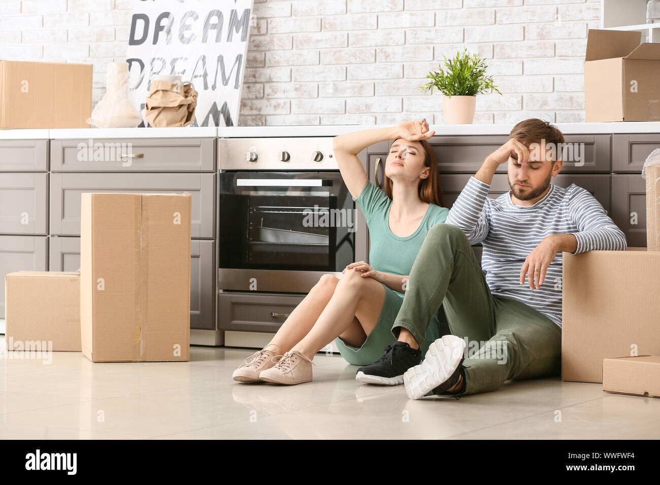 Tired couple sitting on floor after moving into new house Stock Photo ...