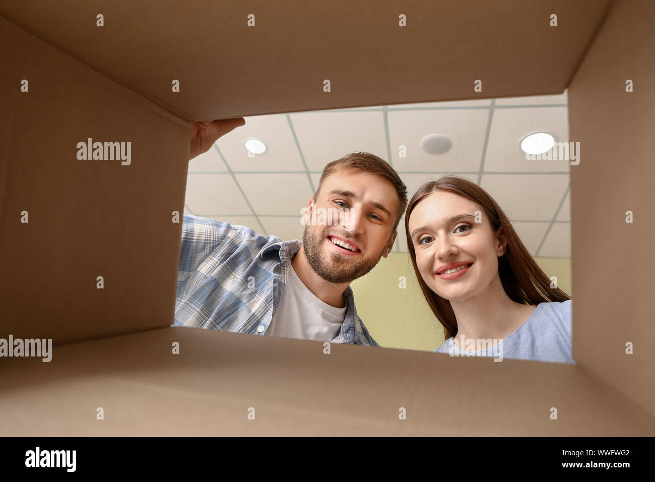 Happy young couple with open moving box, view from inside Stock Photo ...