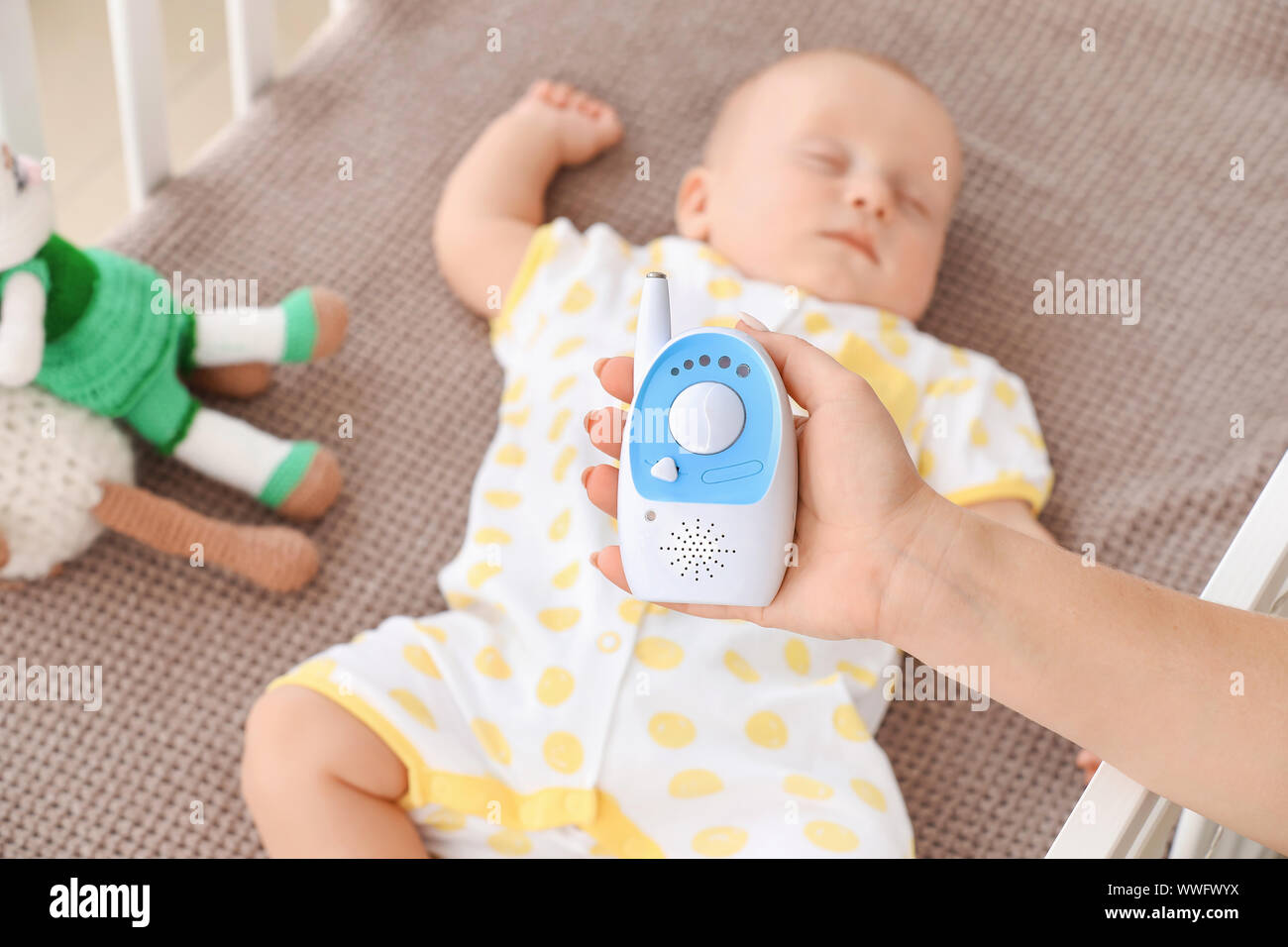 Female hand with modern baby monitor and little sleeping child on ...