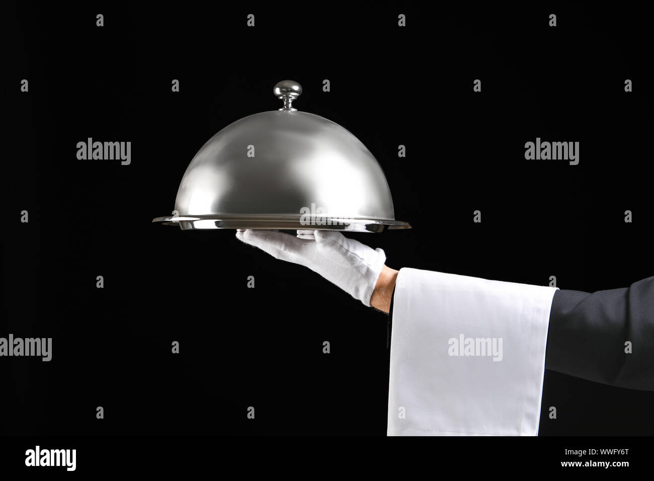 Hand of waiter with tray and cloche on dark background Stock Photo - Alamy