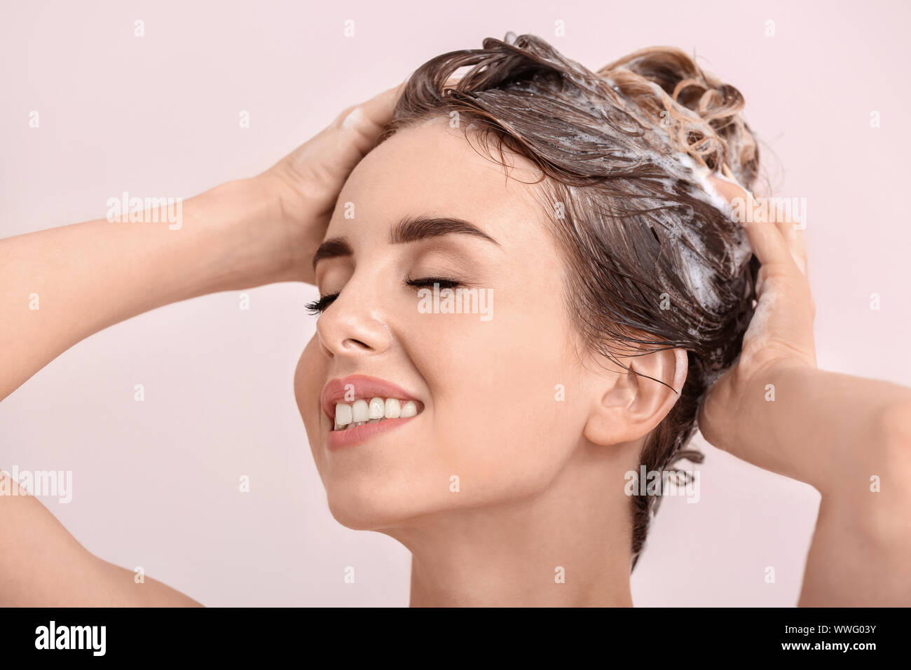 Beautiful young woman washing hair against light color background Stock ...