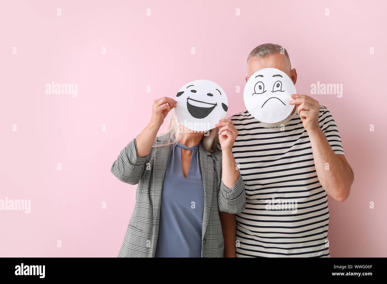 Mature couple hiding faces behind emoticons on color background Stock ...