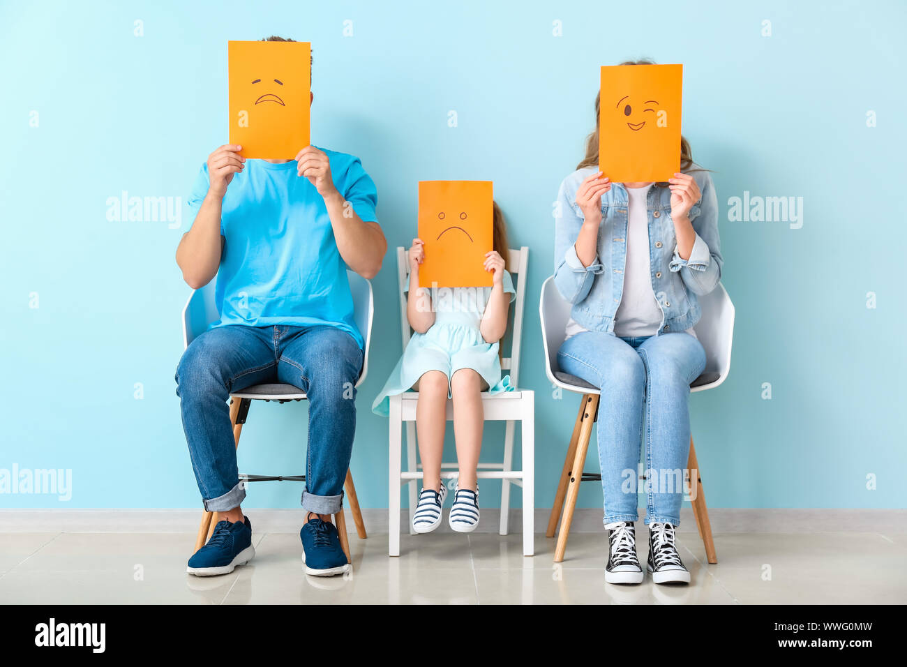 Young family hiding faces behind emoticons near color wall Stock Photo ...