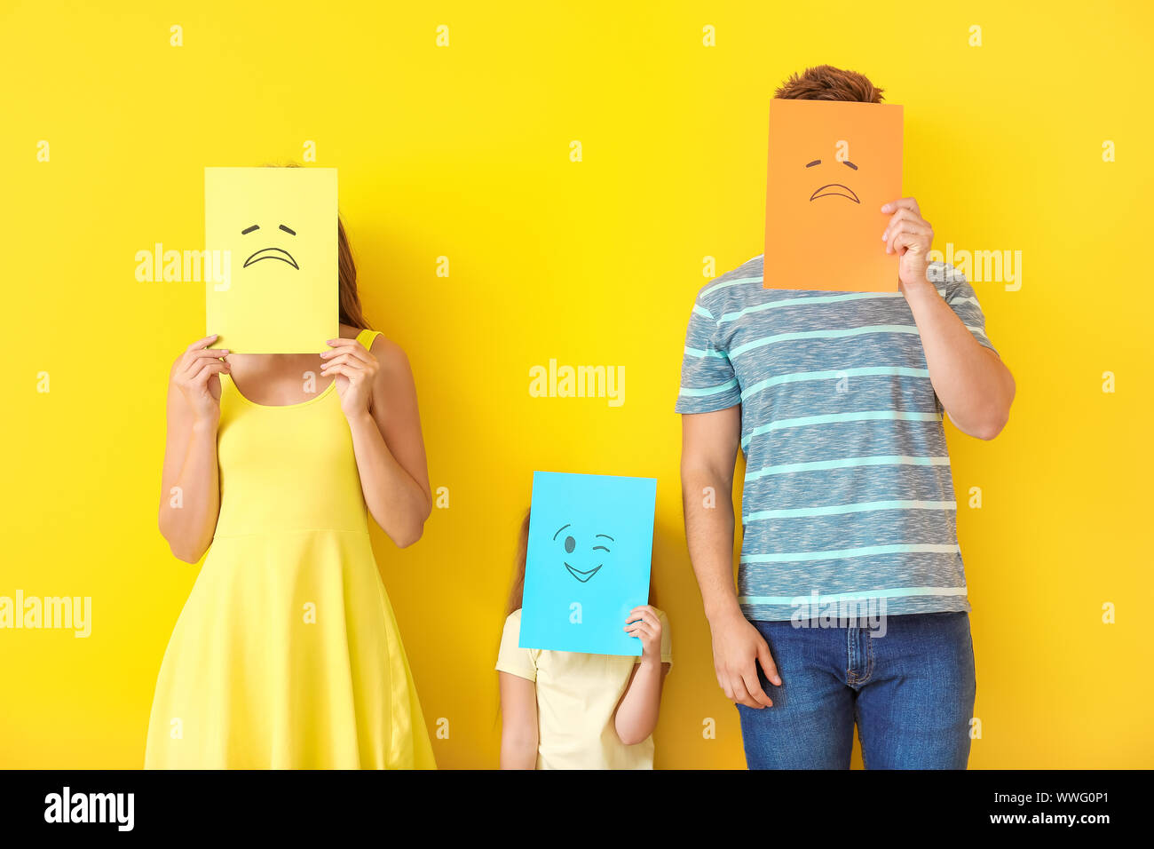 Family hiding faces behind emoticons against color background Stock ...