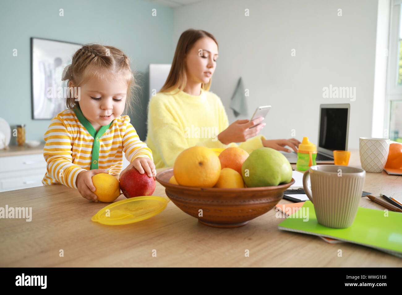 Little daughter with working mother in kitchen at home Stock Photo - Alamy