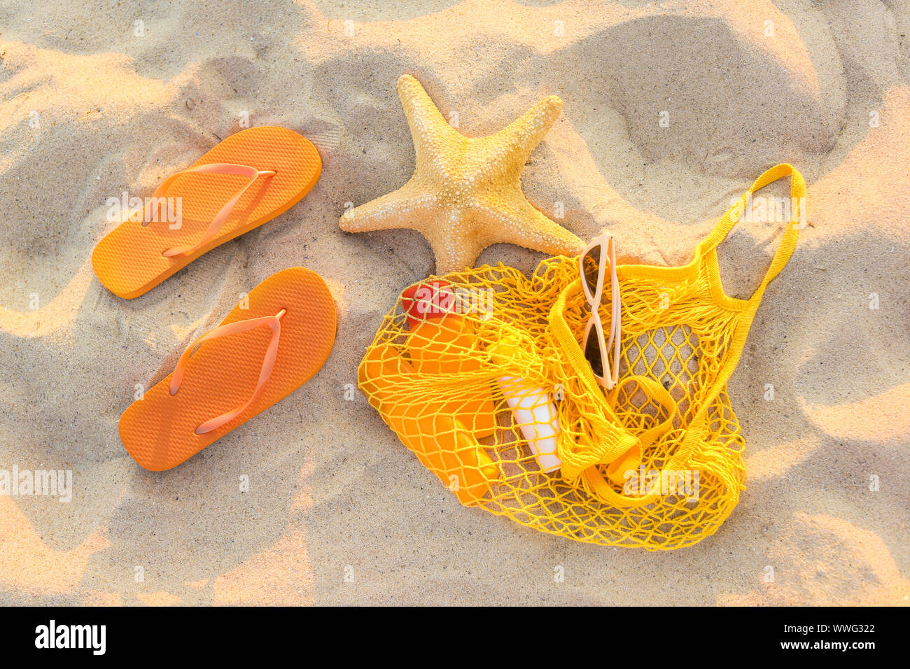 Flip-flops with mesh bag, sunglasses and cosmetics on sand beach Stock ...