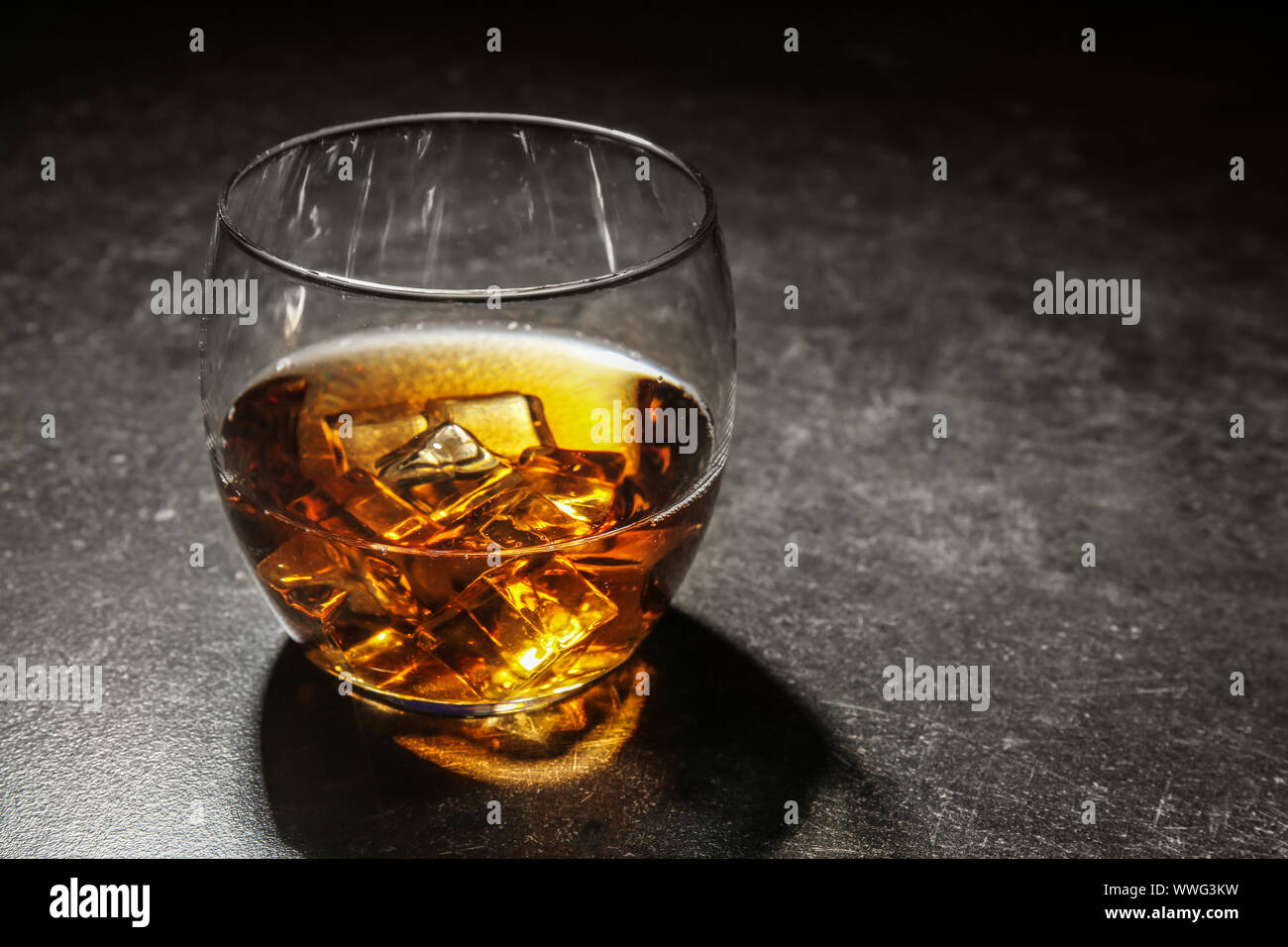 Glass of cold whiskey with ice on dark table Stock Photo - Alamy