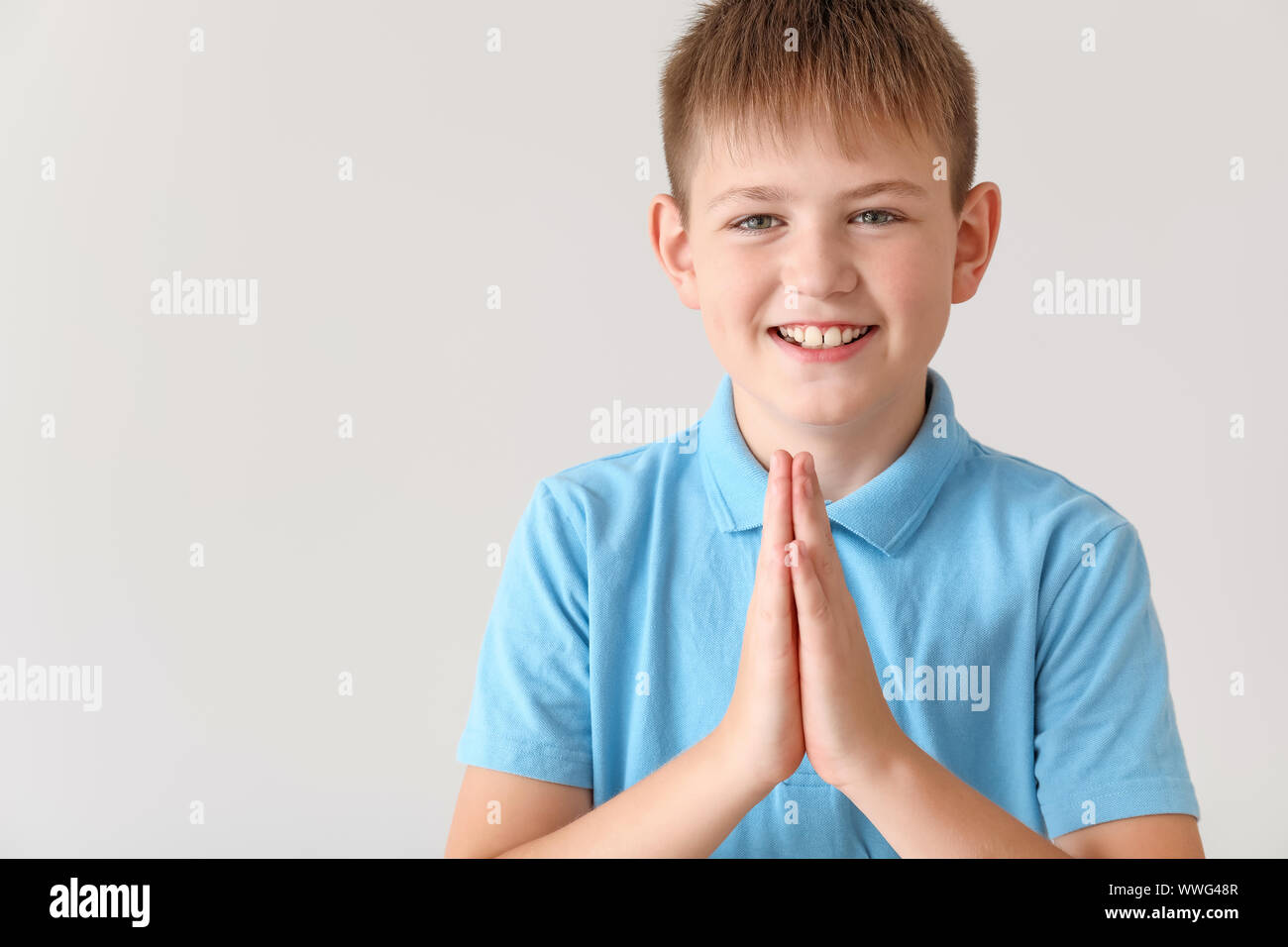 Praying little boy on light background Stock Photo - Alamy
