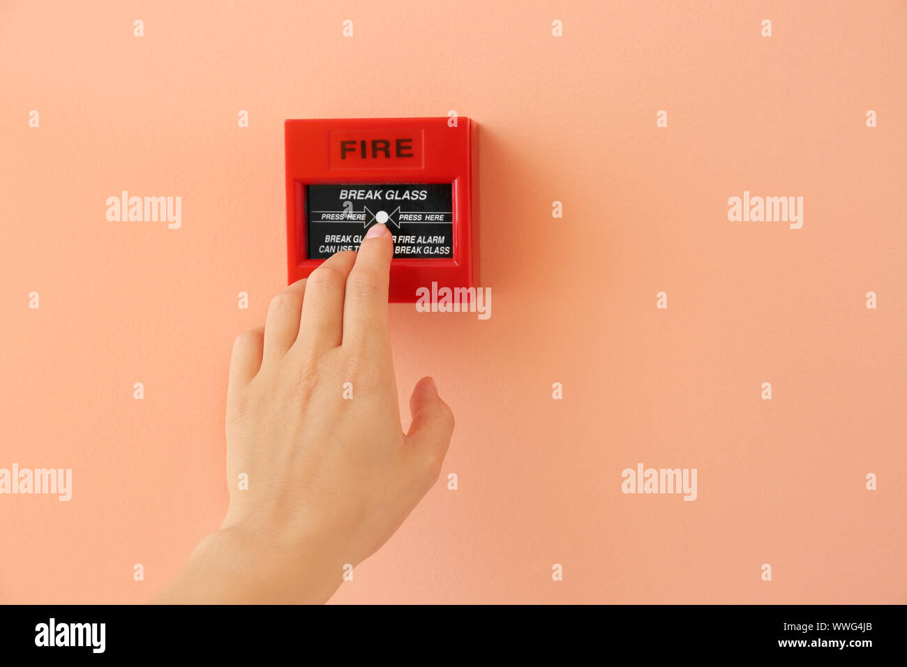 Woman using manual call point of fire alarm system Stock Photo - Alamy