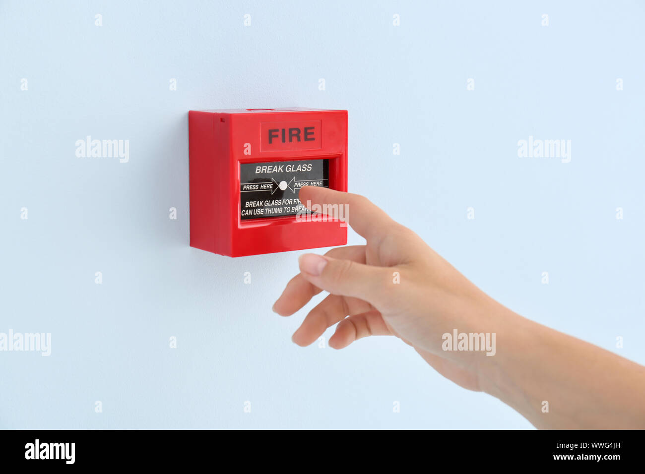 Woman using manual call point of fire alarm system Stock Photo - Alamy