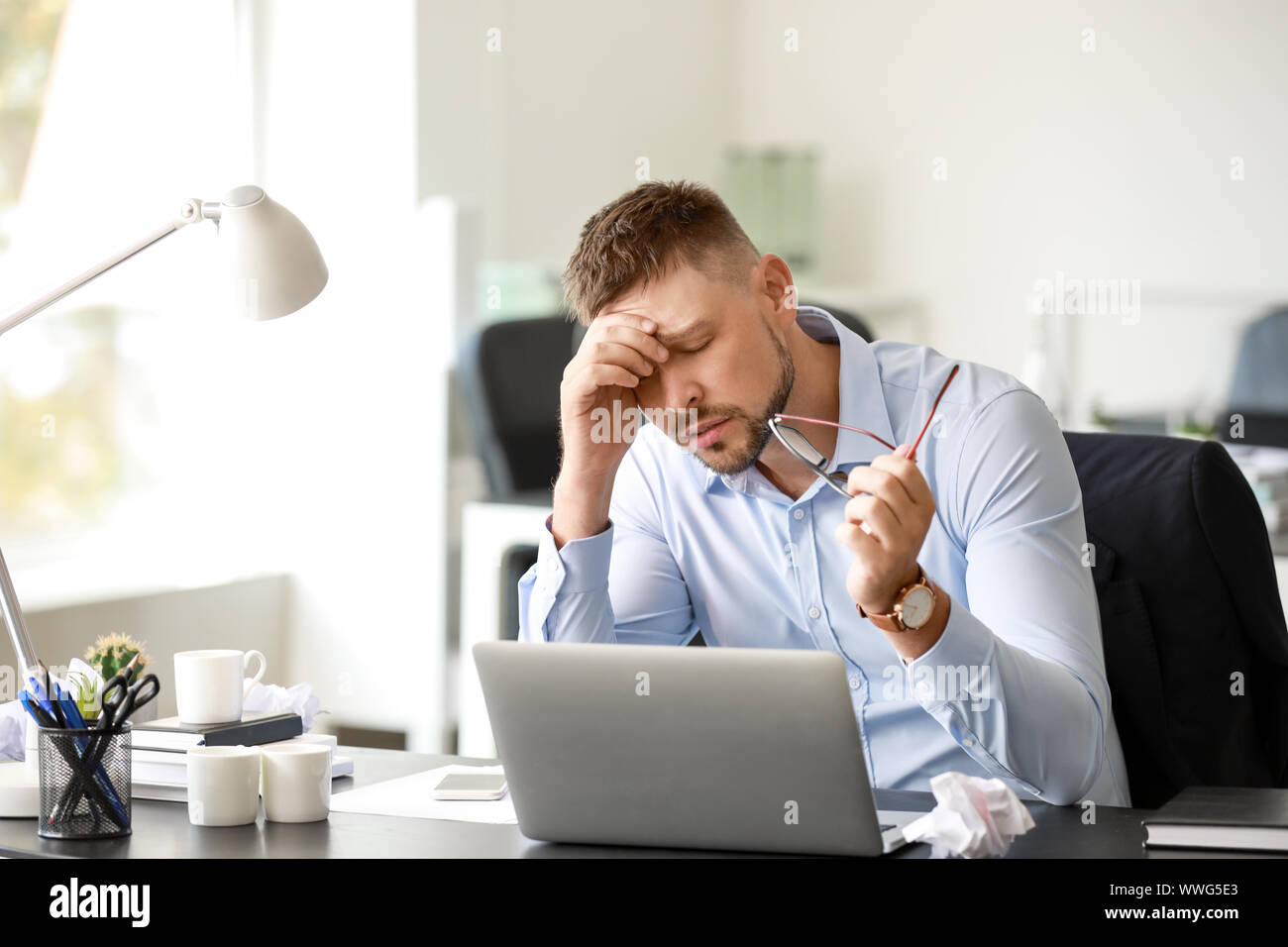 Stressed man at table in office Stock Photo - Alamy