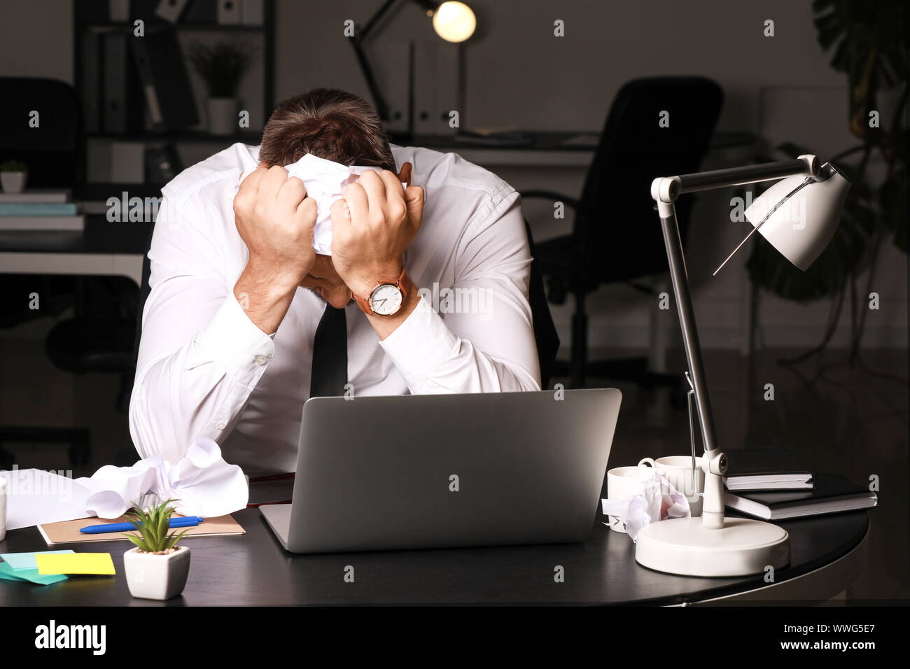 Stressed man at workplace late in evening Stock Photo - Alamy