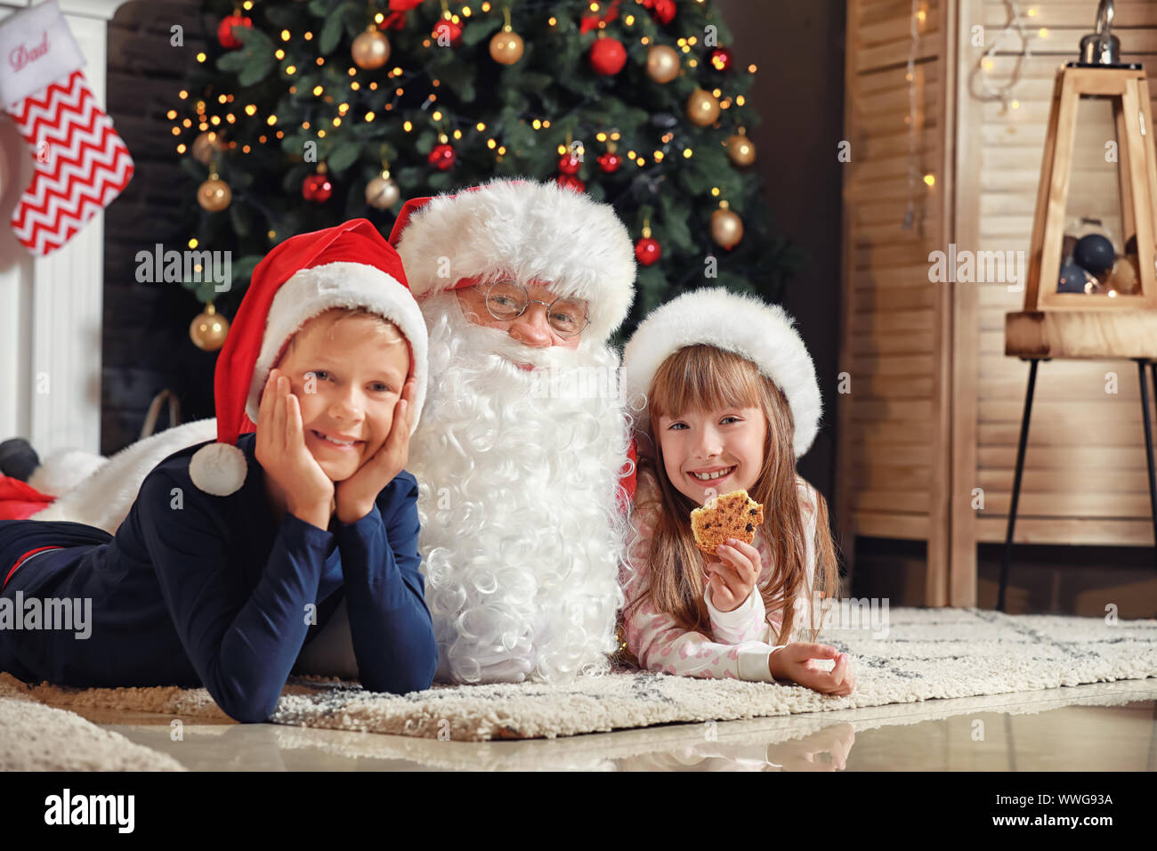Santa Claus and little children in room decorated for Christmas Stock ...