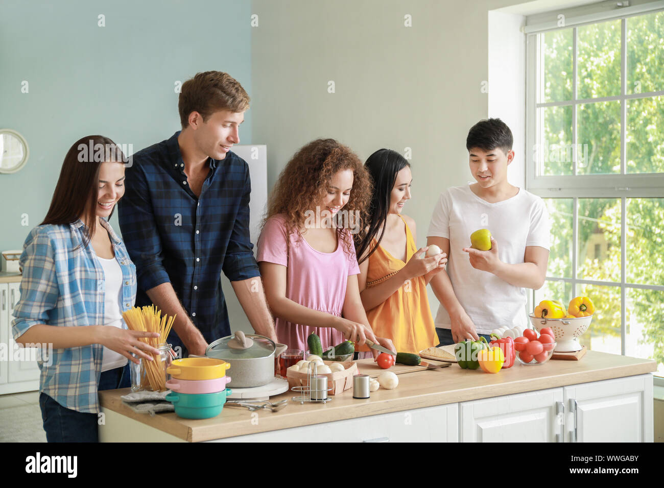 Happy friends cooking together in kitchen Stock Photo - Alamy