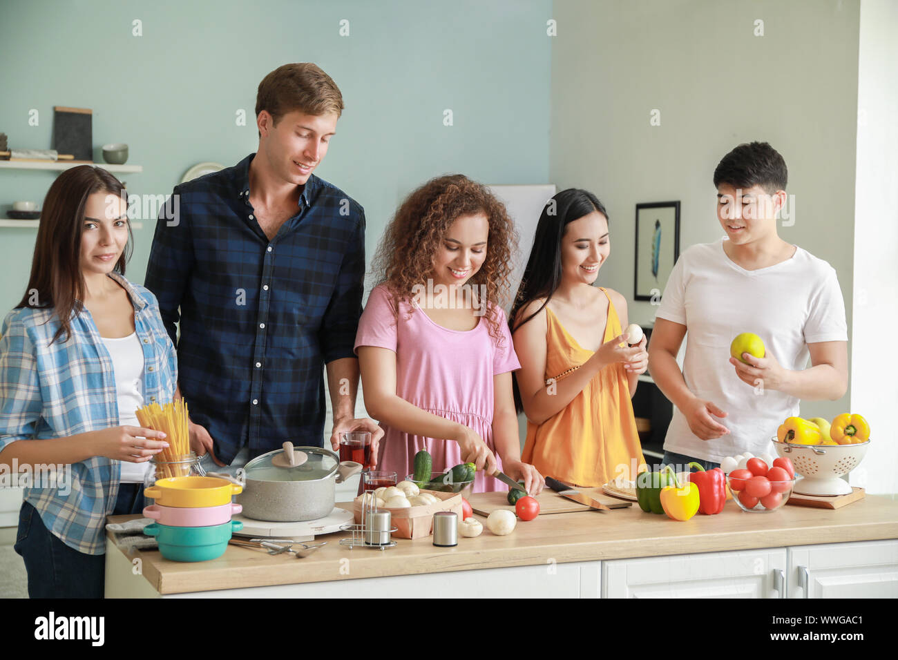 Happy friends cooking together in kitchen Stock Photo - Alamy