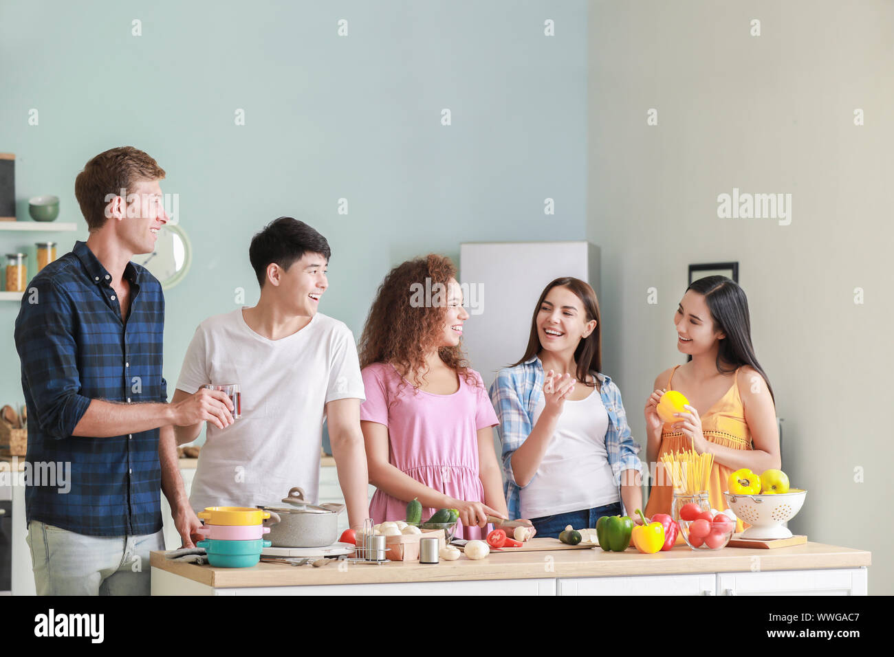 Happy friends cooking together in kitchen Stock Photo - Alamy