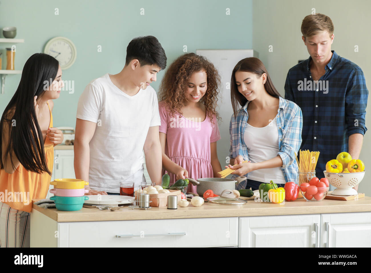 Happy friends cooking together in kitchen Stock Photo - Alamy